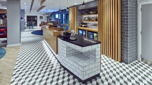 Uma área de bar moderna com bancada preta, painel de azulejos e divisória de ripas de madeira.