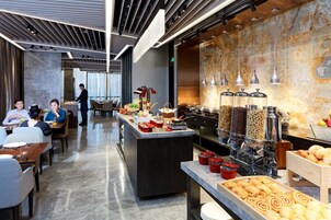 Uma sala de jantar moderna com uma ilha central, disposição de assentos e área de cozinha com luminárias pendentes.