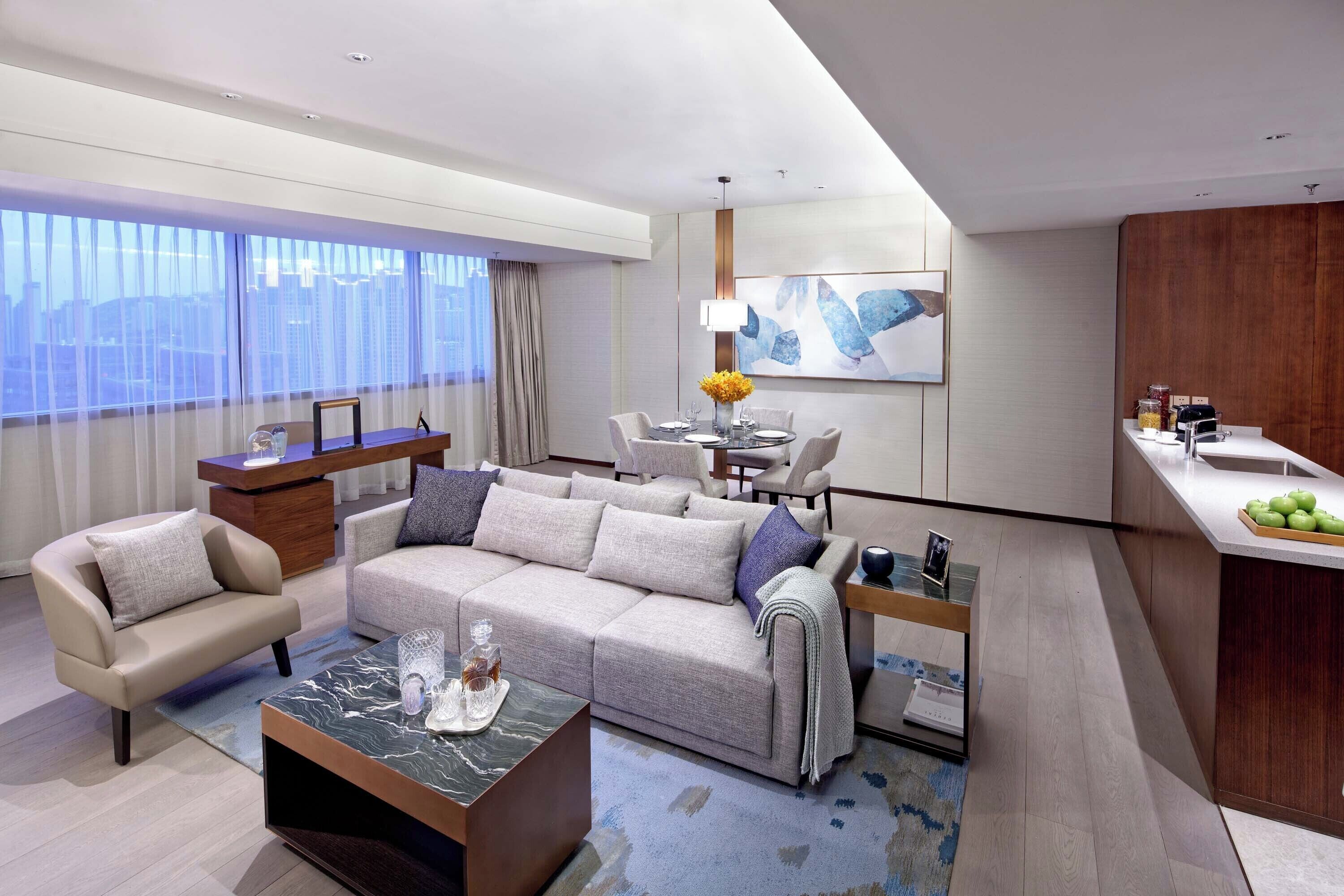 Quarto de hotel moderno com sofá, mesa de centro, mesa de jantar e cozinha.