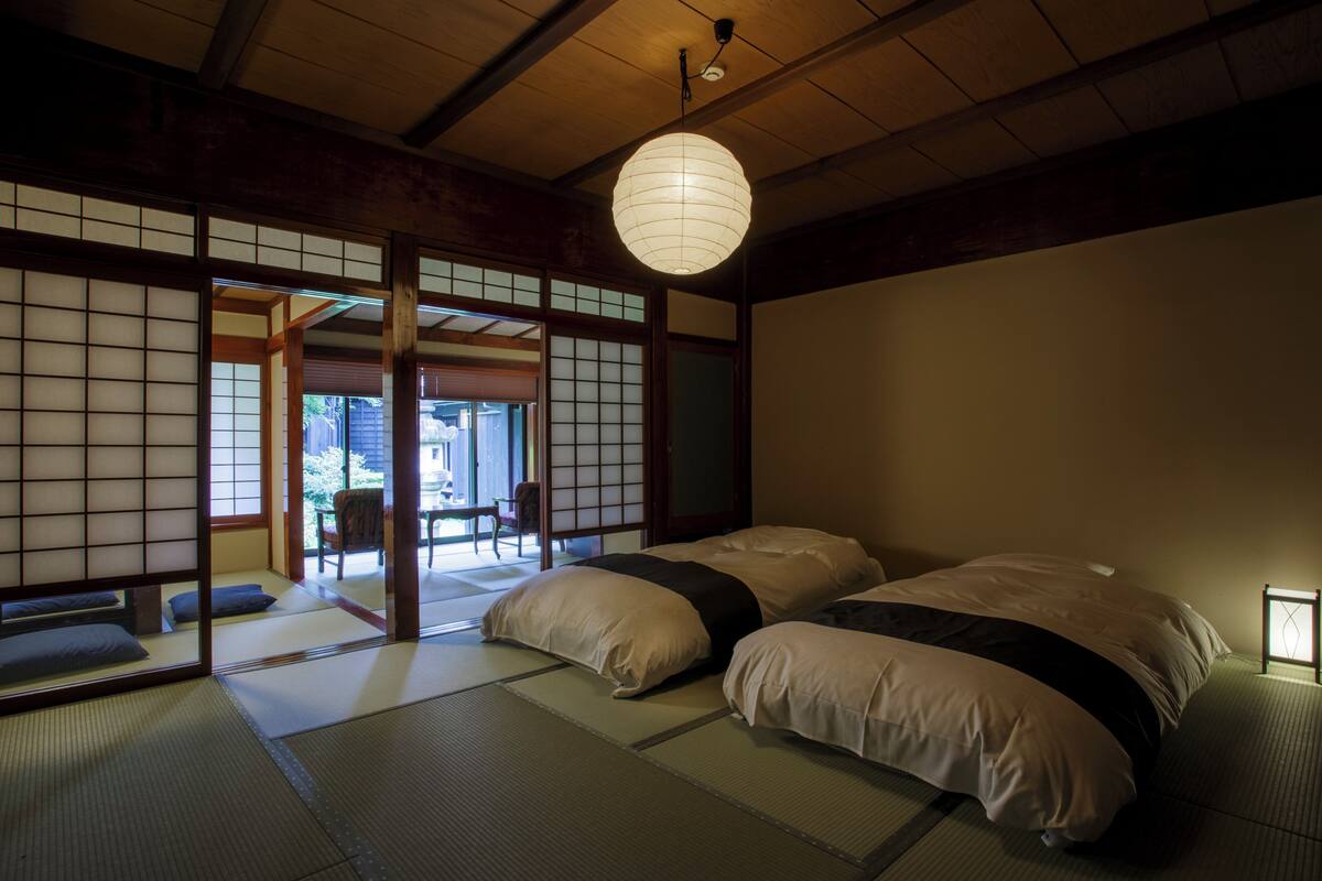Um quarto tradicional japonês com tatames, um biombos shoji e um lanterna de papel pendurada.