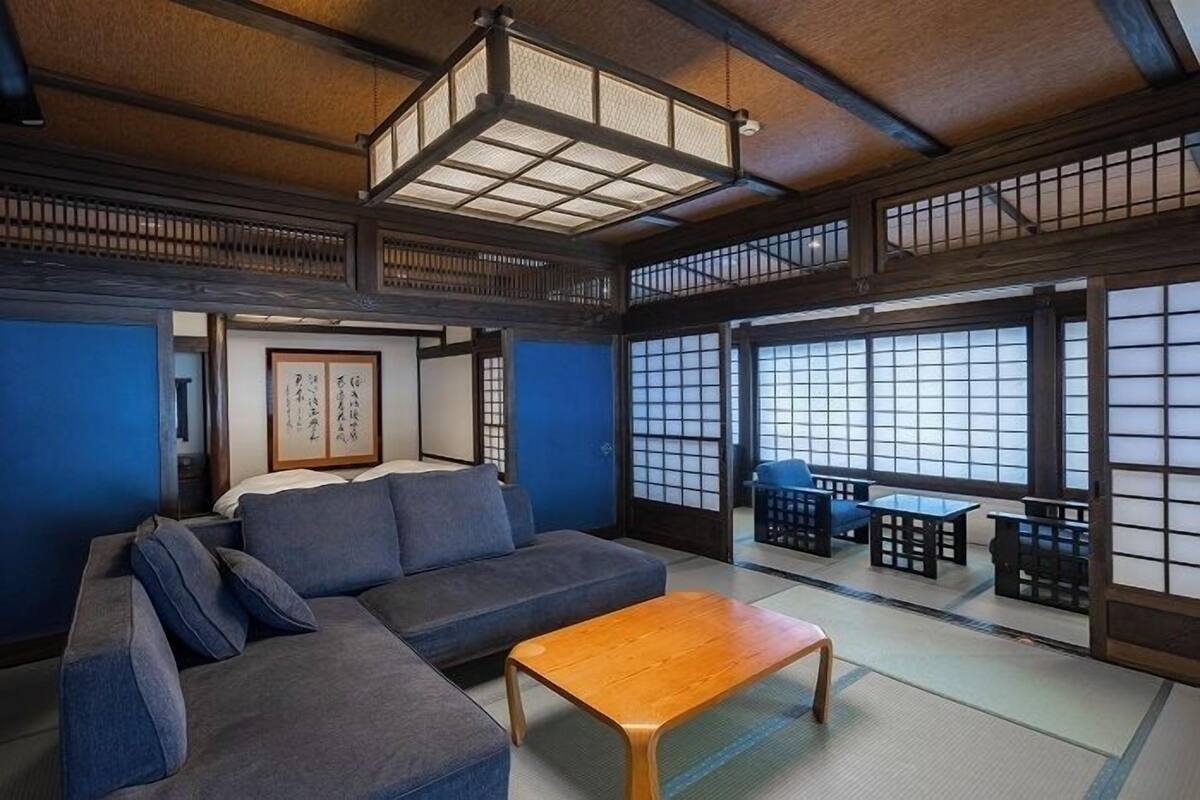 Um quarto japonês tradicional com tatames, uma mesa de madeira baixa, um sofá e portas deslizantes.