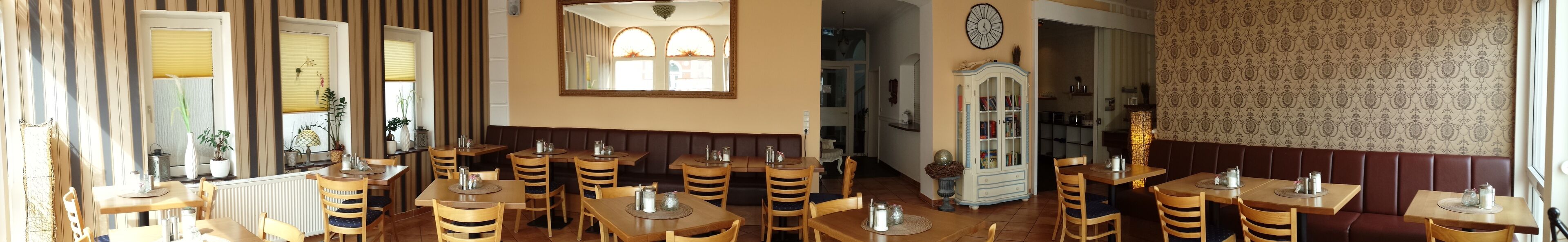 Um restaurante com várias mesas e cabines, cadeiras de madeira e um papel de parede estampado.