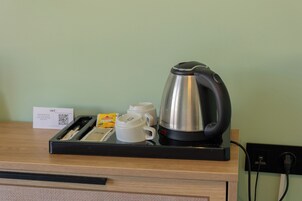 Uma estação de café com chaleira, xícaras e um suporte.