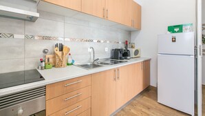 Cozinha moderna com armários de madeira, uma pia de aço inoxidável e uma geladeira branca.