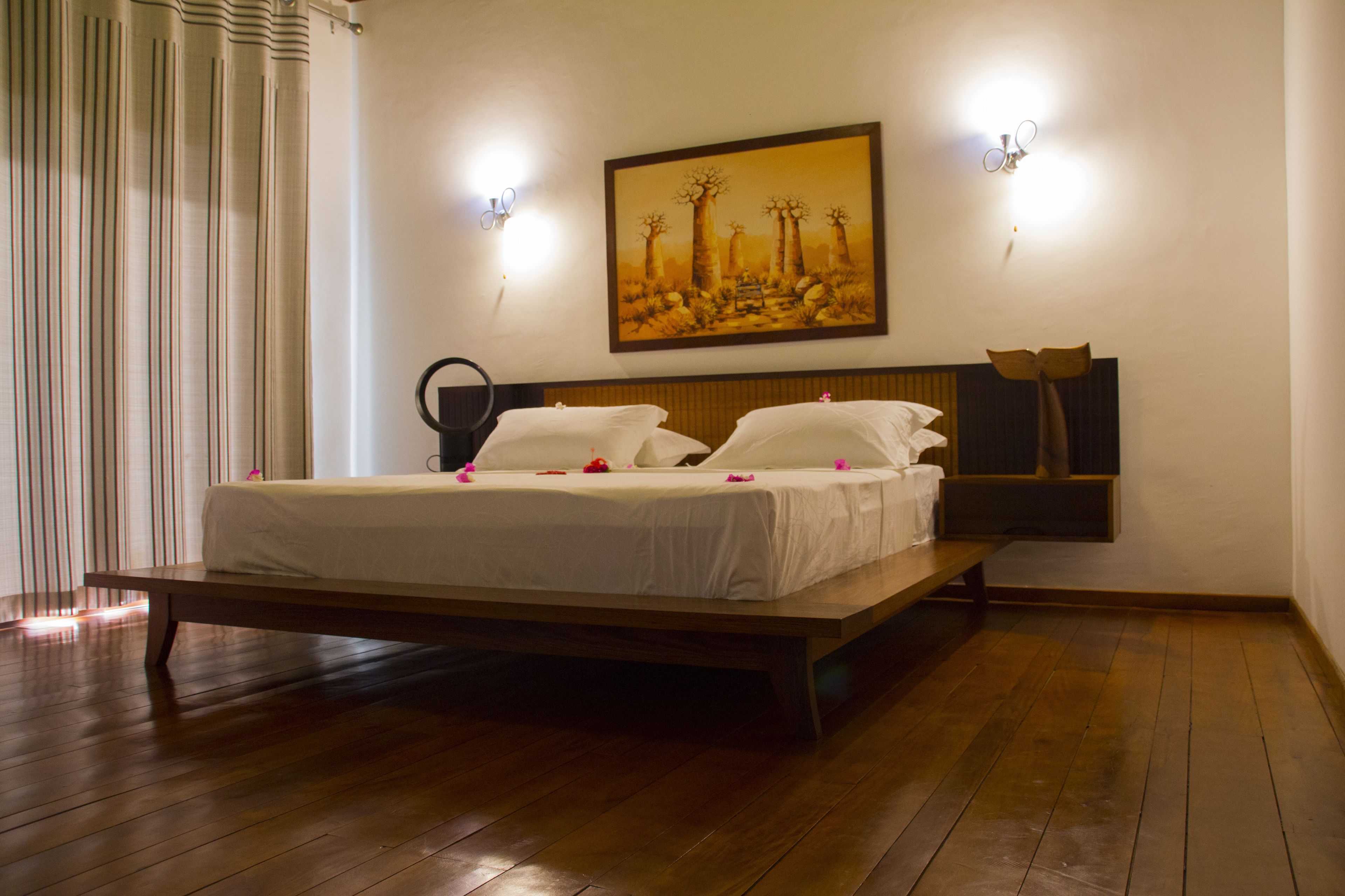 Quarto com uma cama grande, um quadro na parede e um espelho sobre a cama.