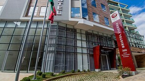 Um hotel moderno com uma placa de destaque, janelas amplas e uma área de entrada bem cuidada.