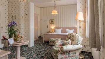 Quarto de hotel com cama, cadeira, mesa com um vaso de flores e abajur.