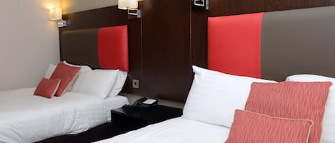 Quarto de hotel com duas camas, roupa de cama vermelha e branca, cabeceira de madeira e abajures.
