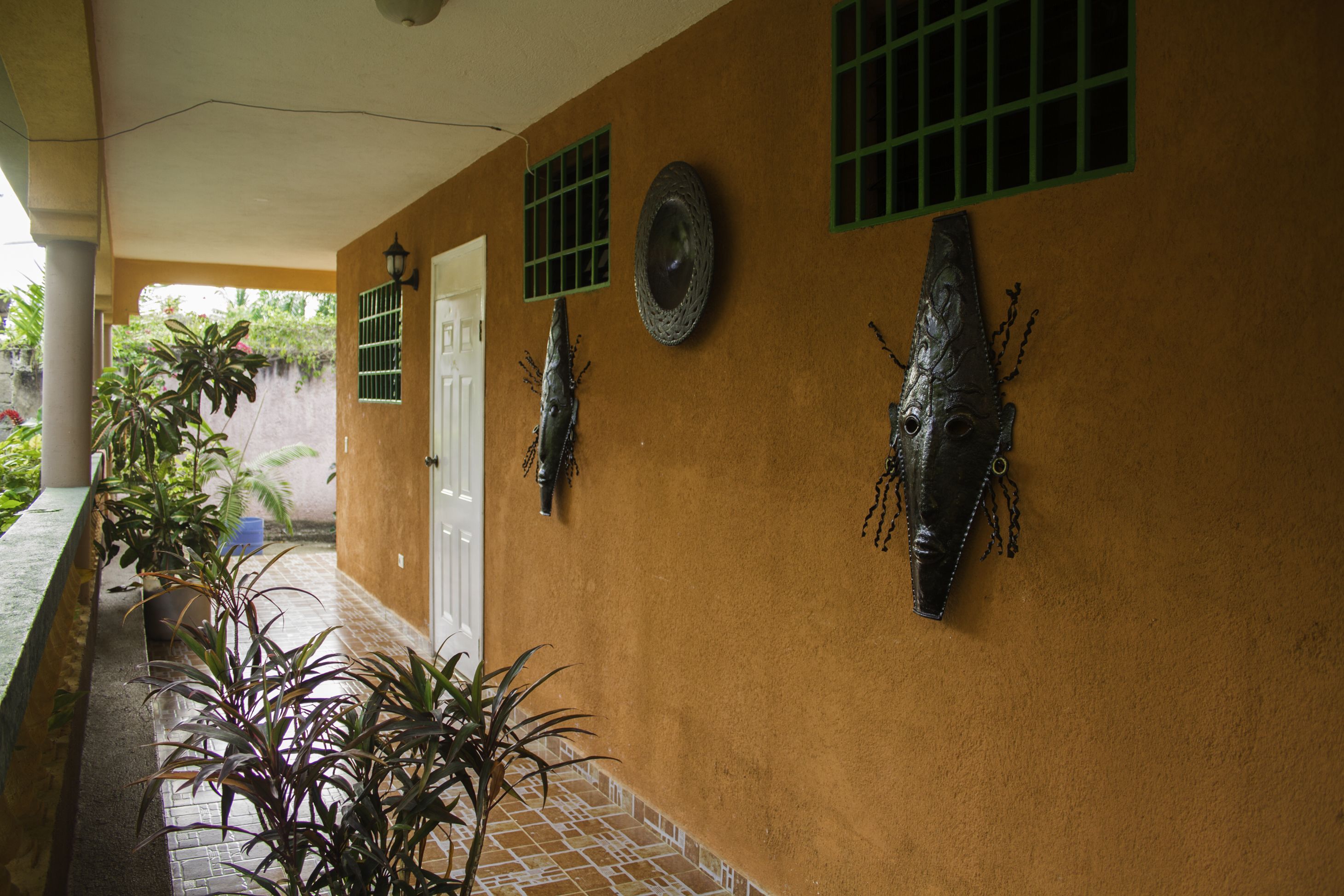 Um corredor com piso de azulejos, uma porta e uma parede com placas de metal decorativas.