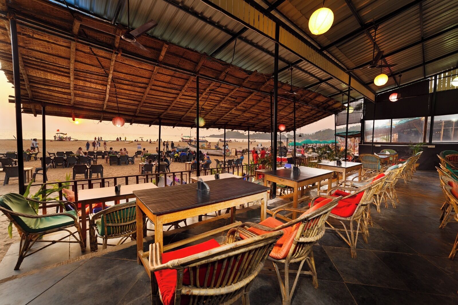 Restaurante ao ar livre com mesas e cadeiras, com vista para a praia.
