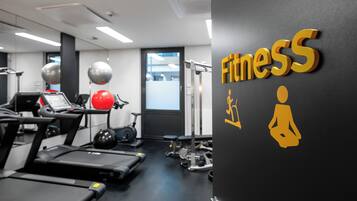 Uma academia com esteiras, bolas de exercícios e máquinas de peso.