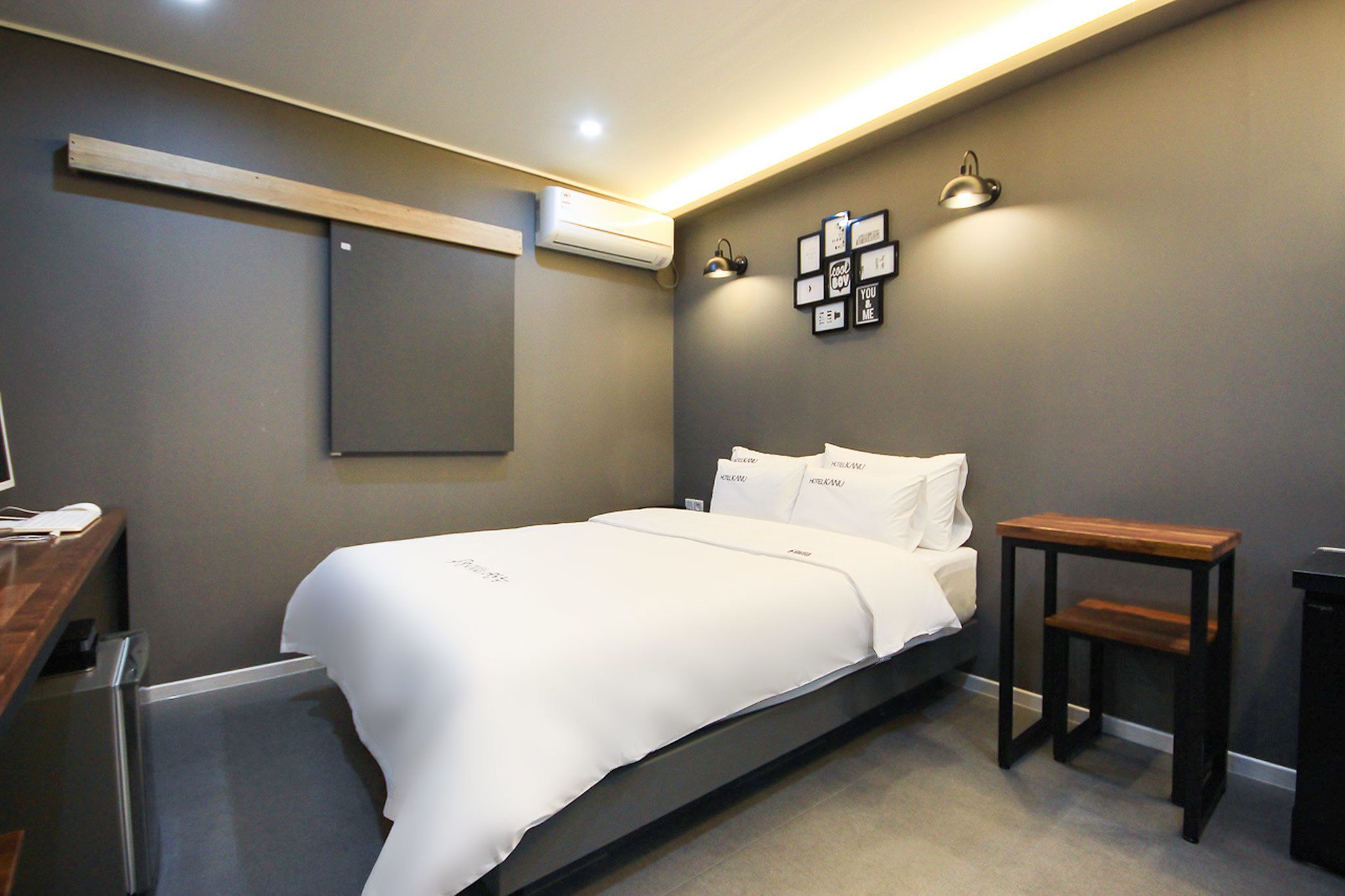 Quarto moderno com cama, mesa de cabeceira e ar condicionado fixado na parede.