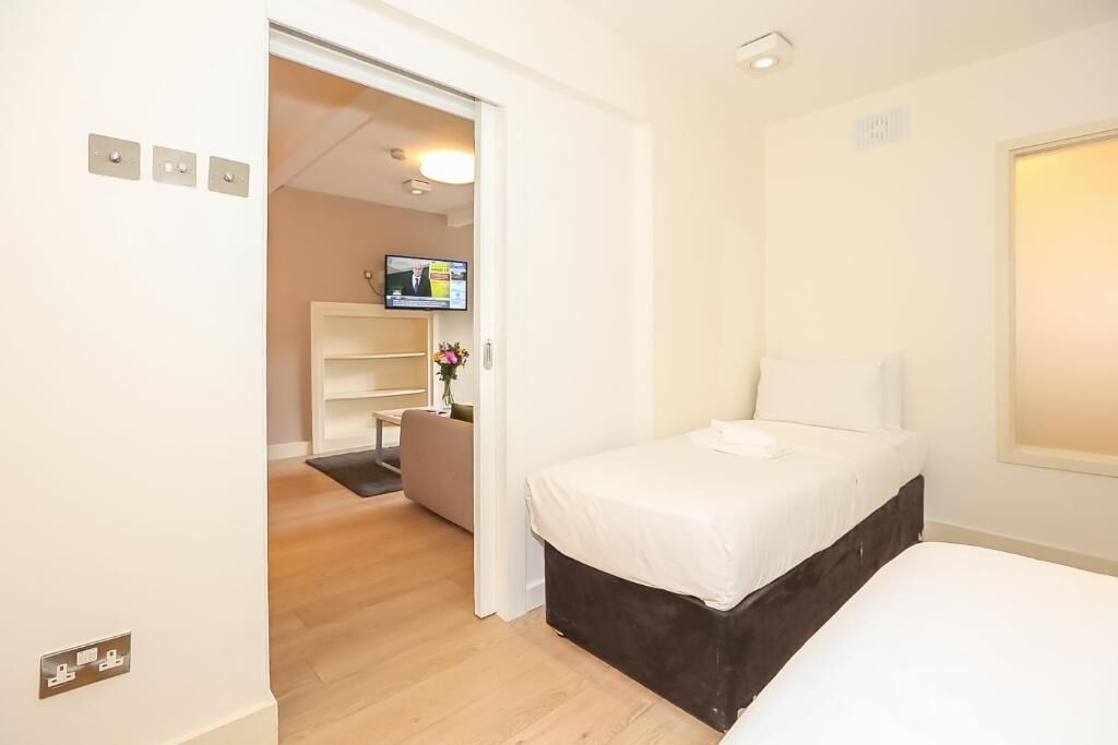 Quarto de hotel com cama, televisão, escrivaninha e cadeira.