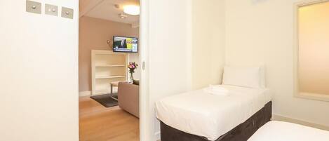 Quarto de hotel com cama, televisão, escrivaninha e cadeira.