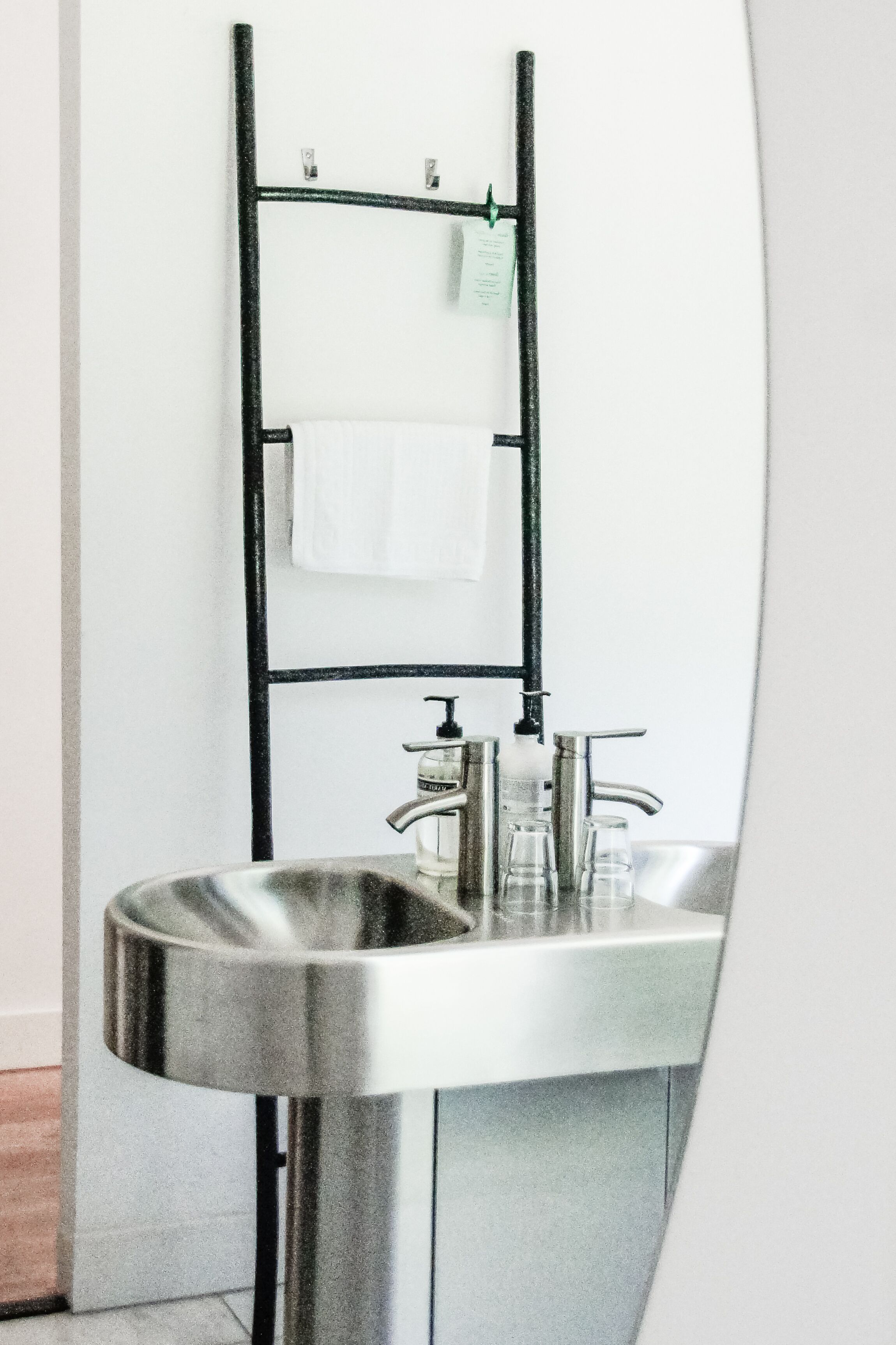 Um banheiro com pia moderna, uma toalha pendurada em um porta-toalhas e um espelho refletindo a área da pia.