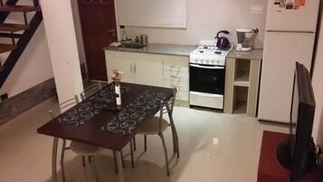 Uma cozinha compacta com mesa, cadeiras, fogão, micro-ondas e geladeira.
