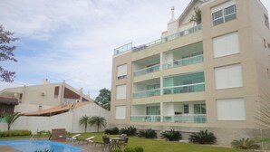 Um edifício com vários andares, piscina e área de estar ao ar livre.