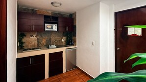 Cozinha compacta com armários escuros, micro-ondas e pia.