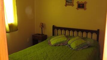 Quarto com uma cama, uma mesa de cabeceira e duas imagens penduradas na parede.