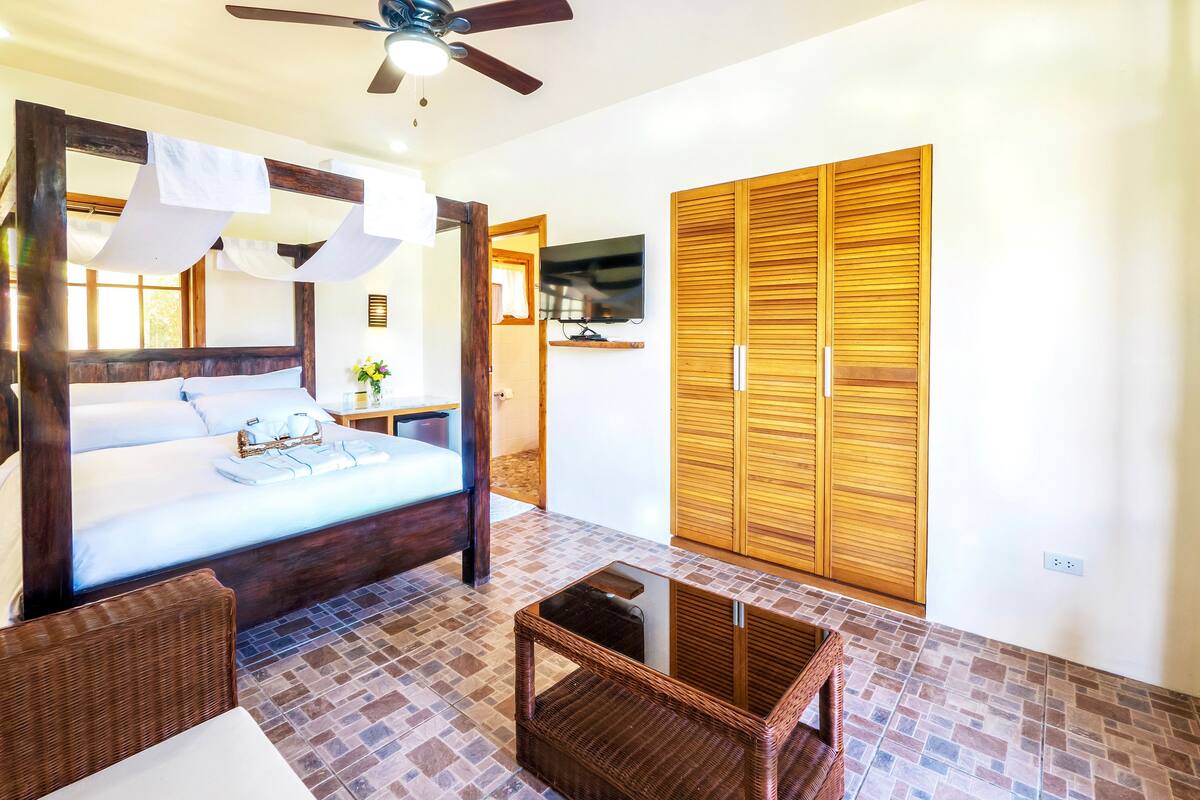 Quarto com uma cama grande, guarda-roupa de madeira e televisão na parede.