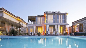 Um hotel grande e moderno com piscina, várias varandas e fachada de pedra.