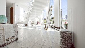 Um amplo saguão de hotel com teto alto, janelas grandes e uma escadaria.