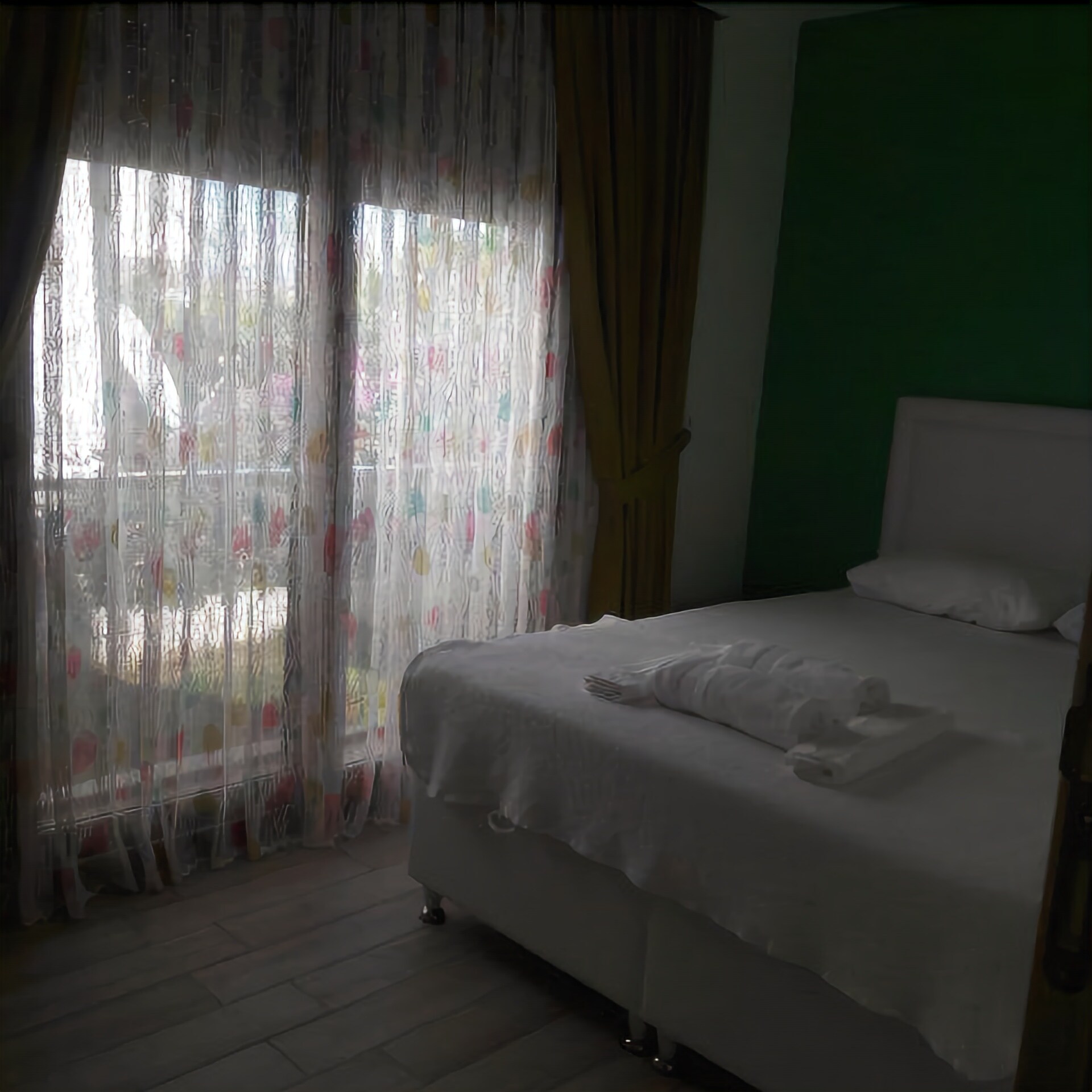 Quarto com cama, cortinas e parede verde.