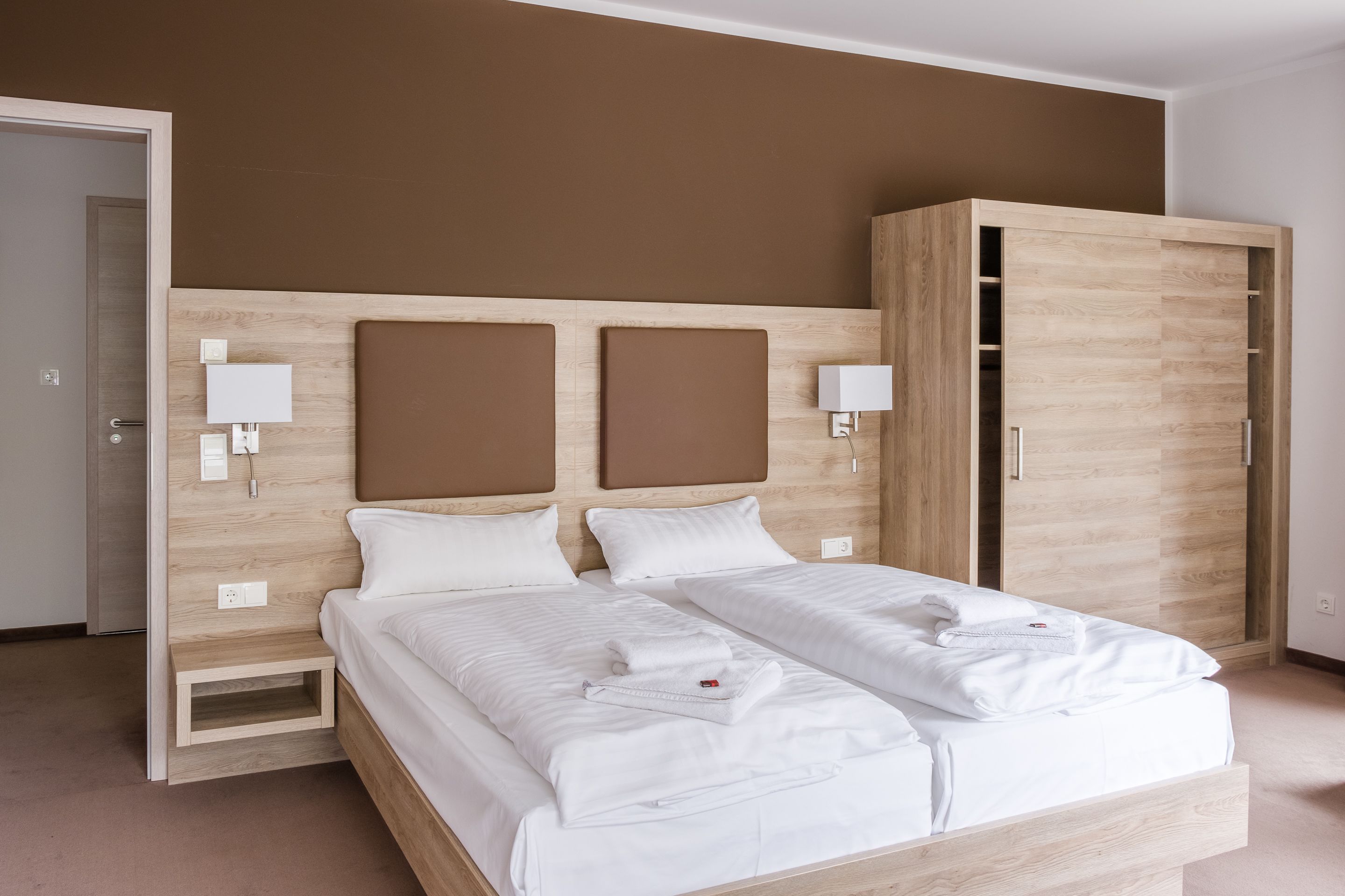 Quarto moderno com cama grande, cabeceira de madeira, abajures e guarda-roupa.