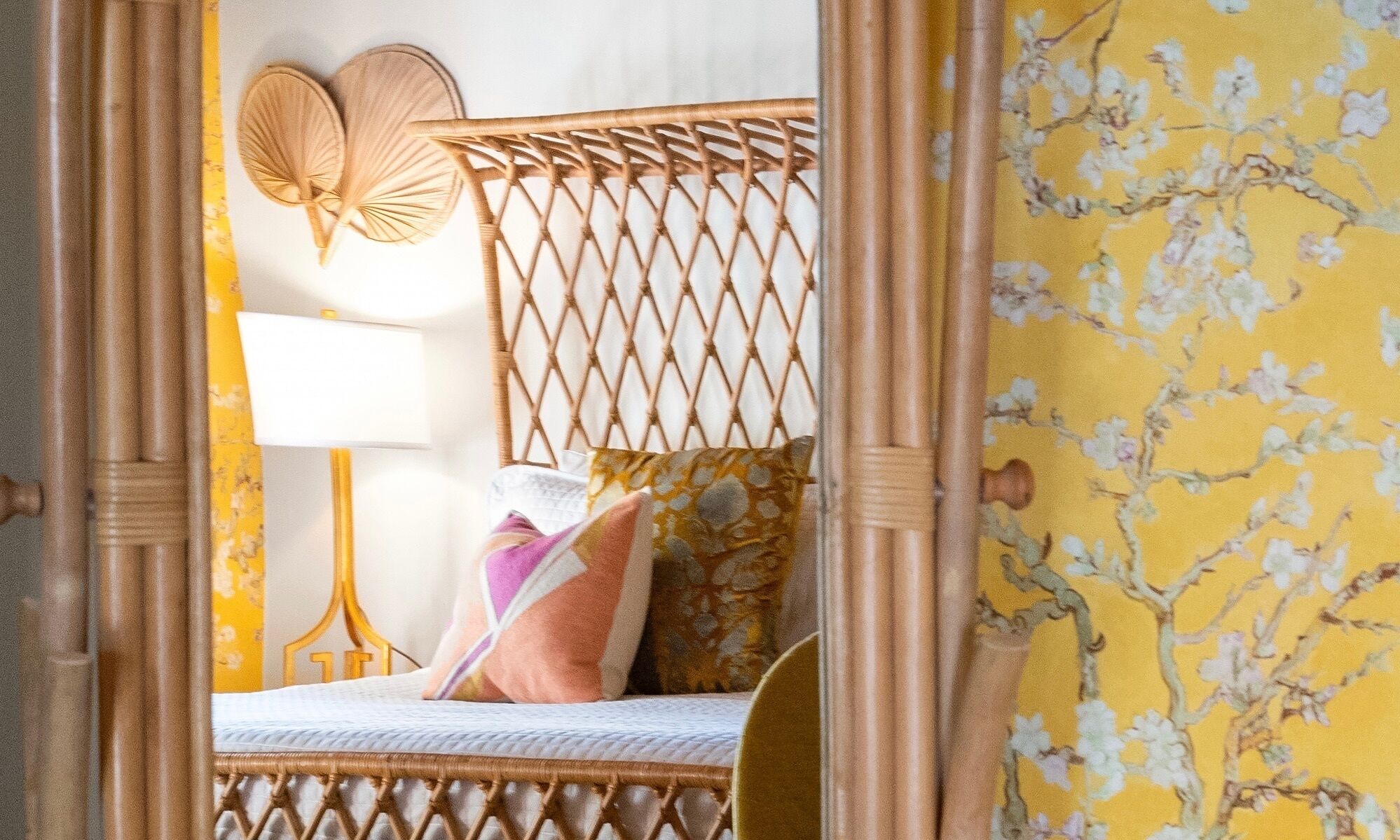 Quarto com cama, luminária e parede estampada com flores.