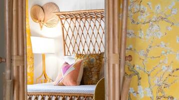 Quarto com cama, luminária e parede estampada com flores.