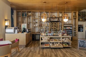 Um café com estantes de madeira repletas de diversos itens, uma máquina de café e um quadro negro com o menu.