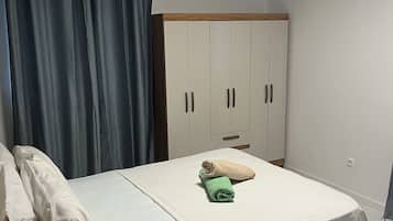 Quarto com cama, guarda-roupa, cortina e luminária de teto.