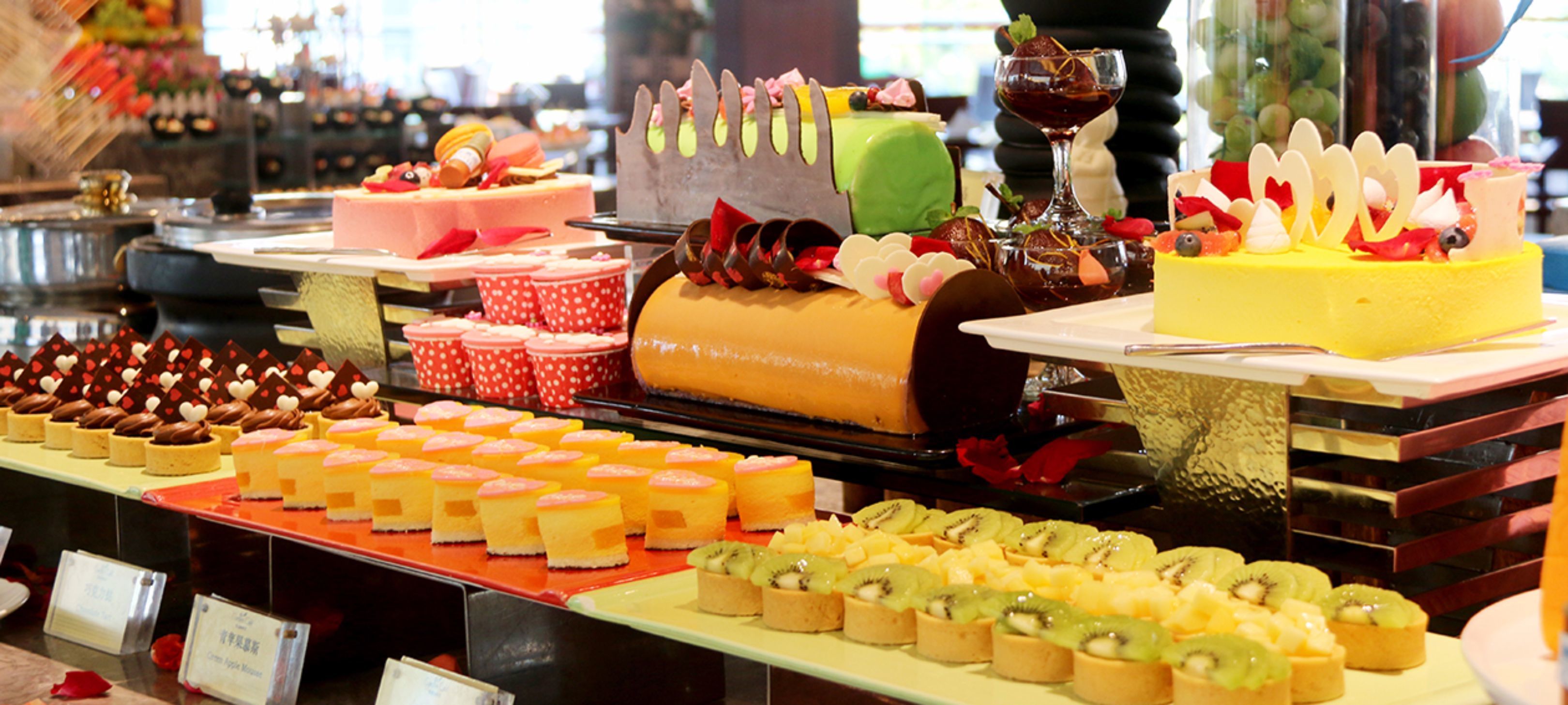 Diversas sobremesas e doces expostos em uma mesa de buffet.