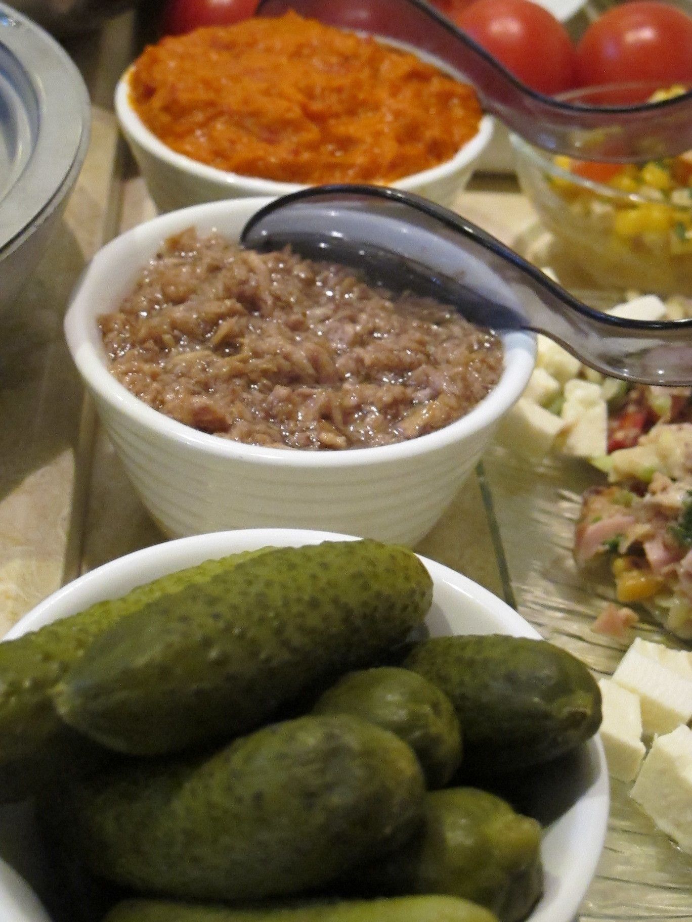 Uma mesa com diversos alimentos, incluindo picles, um prato de feijão e um prato de salsa.
