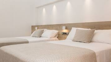 Quarto de hotel com duas camas, cada uma com roupa de cama estampada e cabeceira de madeira.