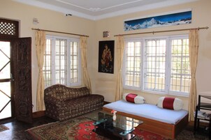 Um quarto com sofá, cama, mesa de centro de vidro e um quadro na parede.