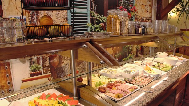 Buffet com diversos alimentos, incluindo frutas, carnes e queijos.