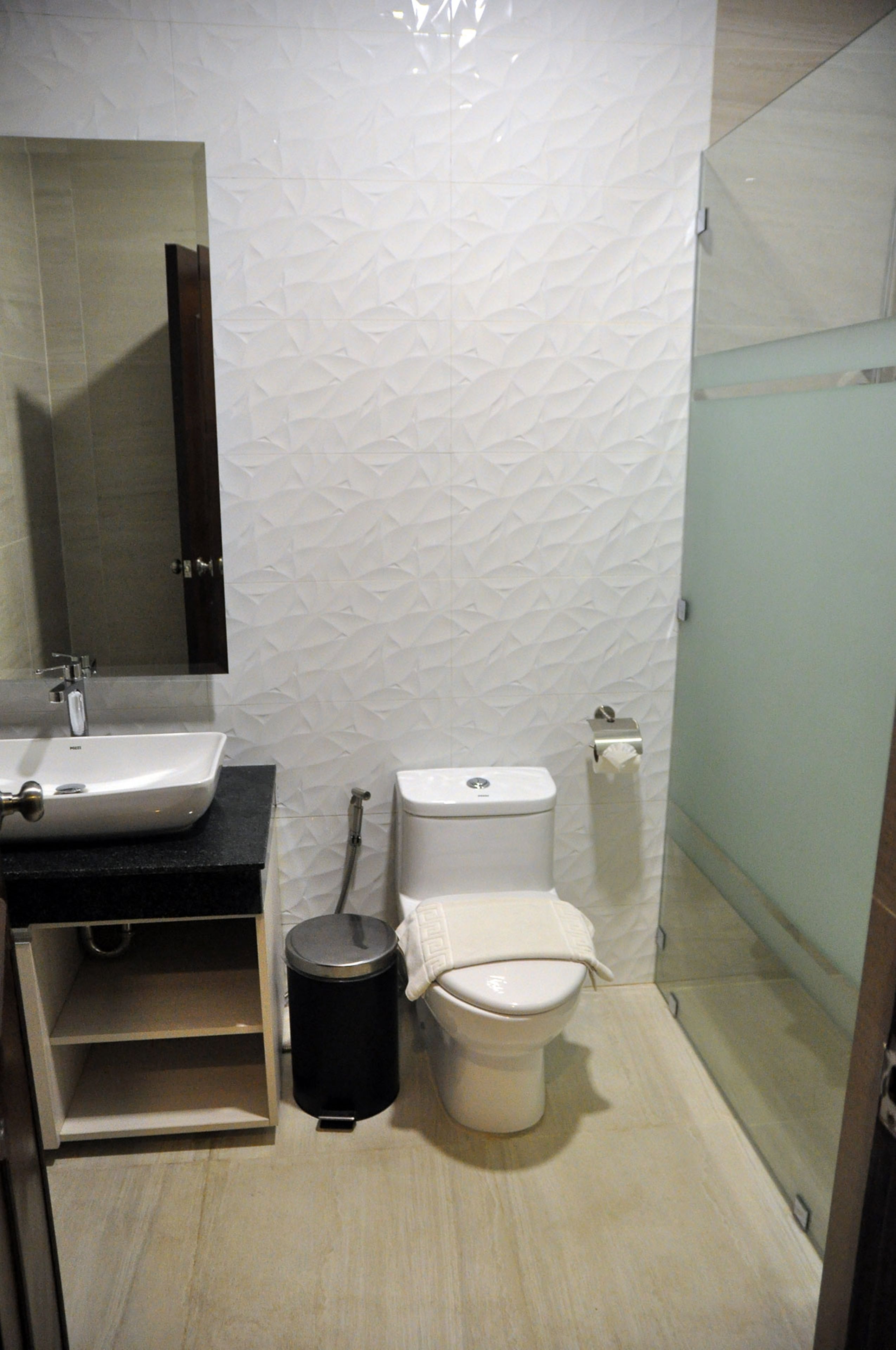 Casa de banho com lavatório branco, sanita e cabine de duche em vidro.
