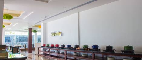 Uma cozinha moderna com uma bancada comprida exibindo diversas panelas e frigideiras, parede branca e um espaço amplo e iluminado.