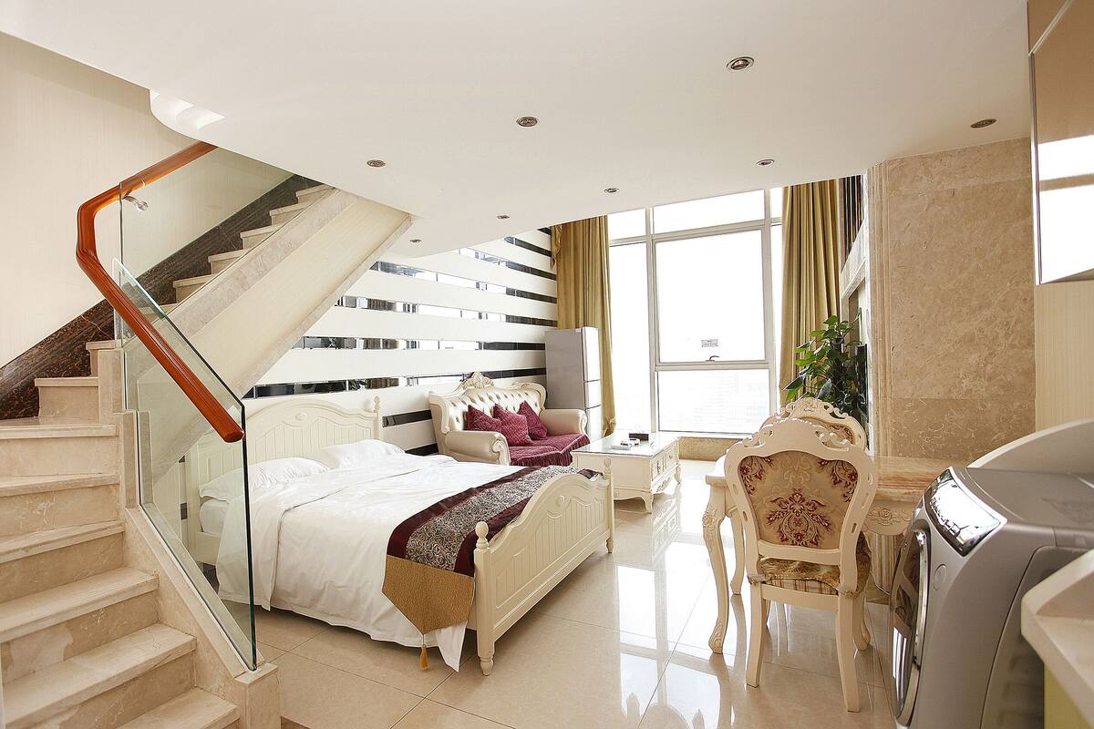 Quarto com cama, cadeira, máquina de lavar e escada.