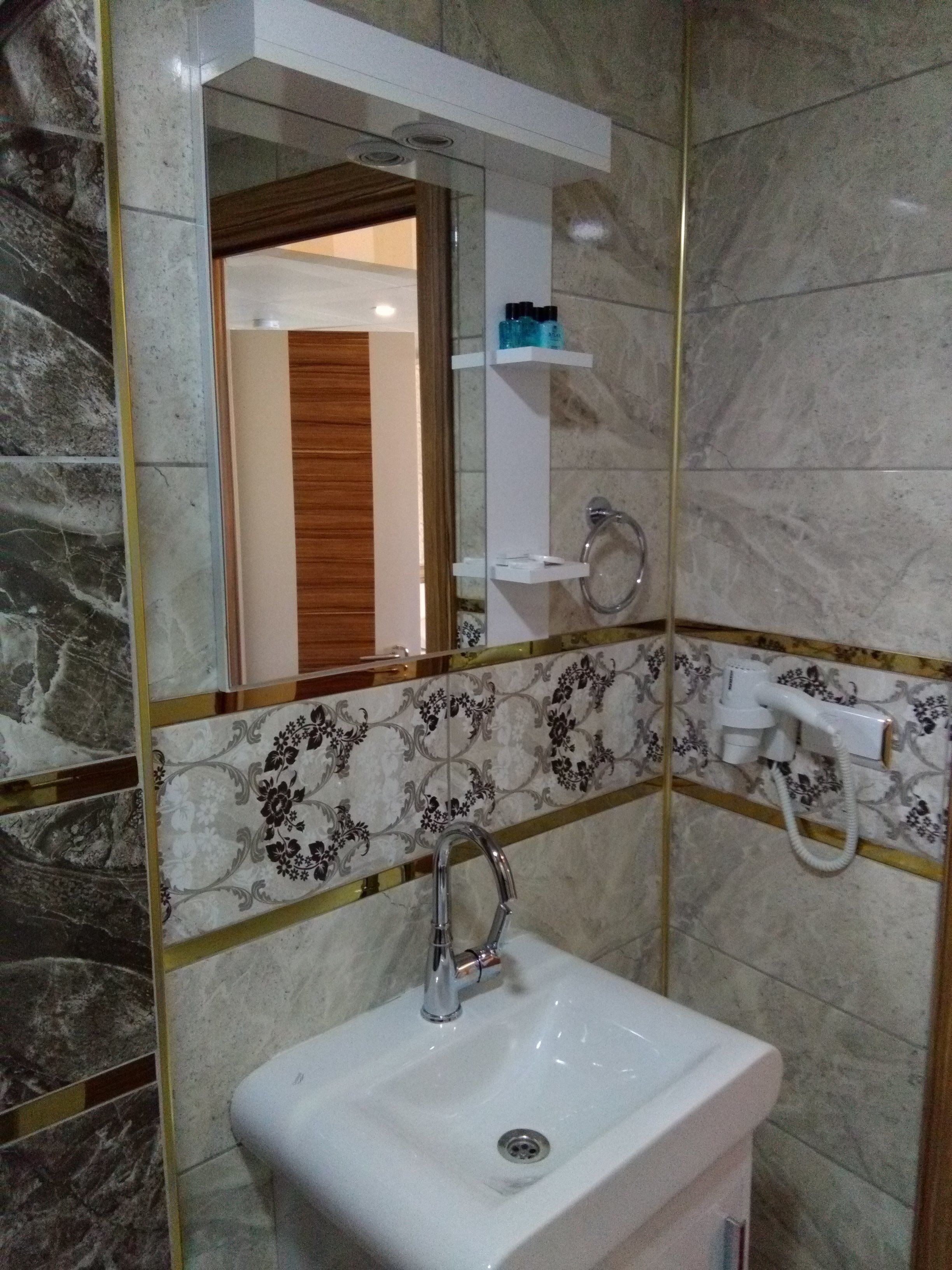 Uma casa de banho com uma pia branca, um espelho e zona de duche.
