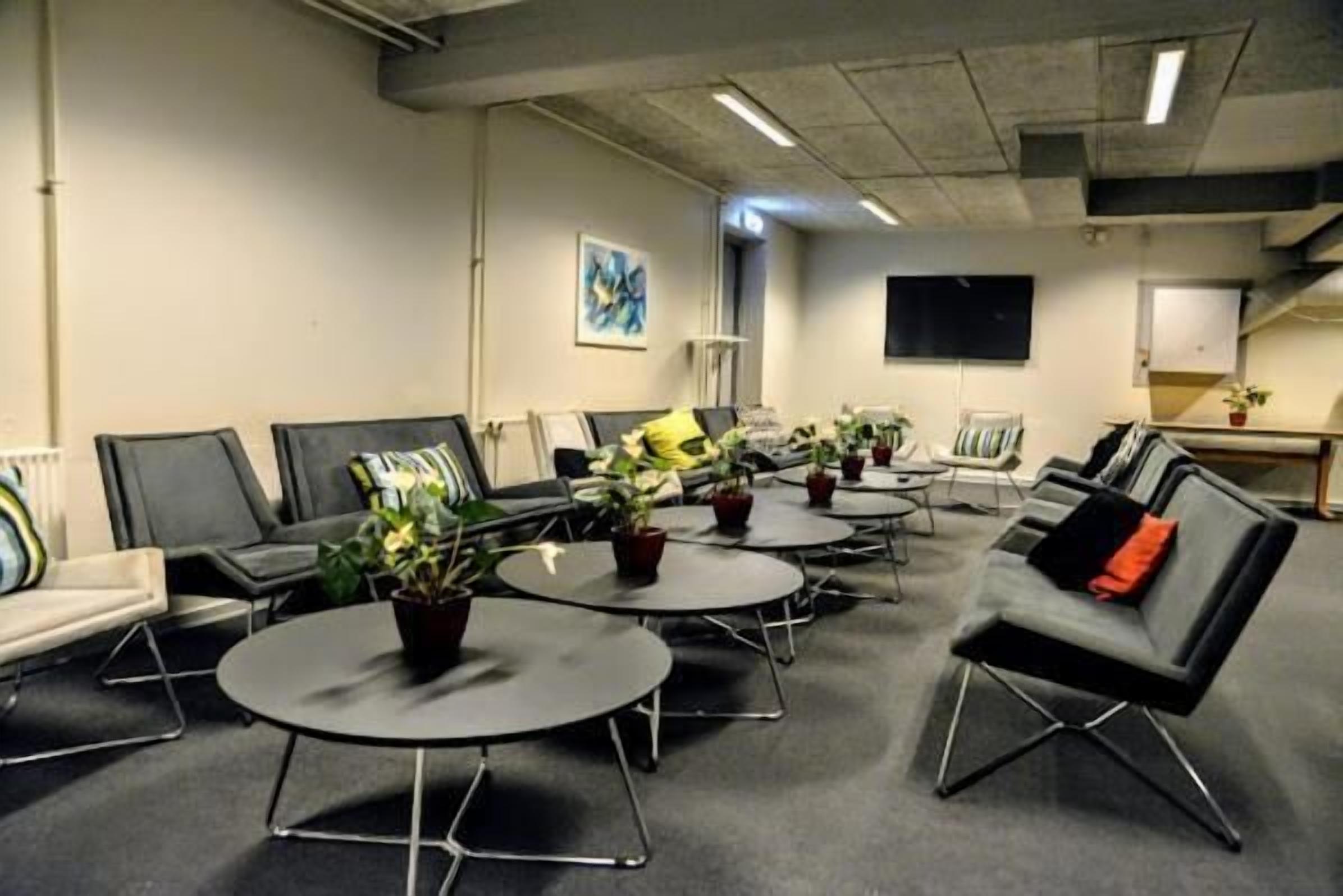 Uma sala de conferências com mesas redondas, cadeiras e plantas em vasos.