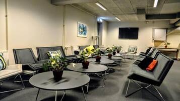 Uma sala de conferências com mesas redondas, cadeiras e plantas em vasos.