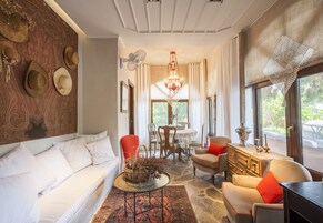 Uma sala de estar aconchegante com sofá, cadeiras, uma mesa de jantar e um lustre.