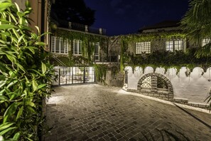 Um pátio com piso de pedras, um arco de pedra e um portão.