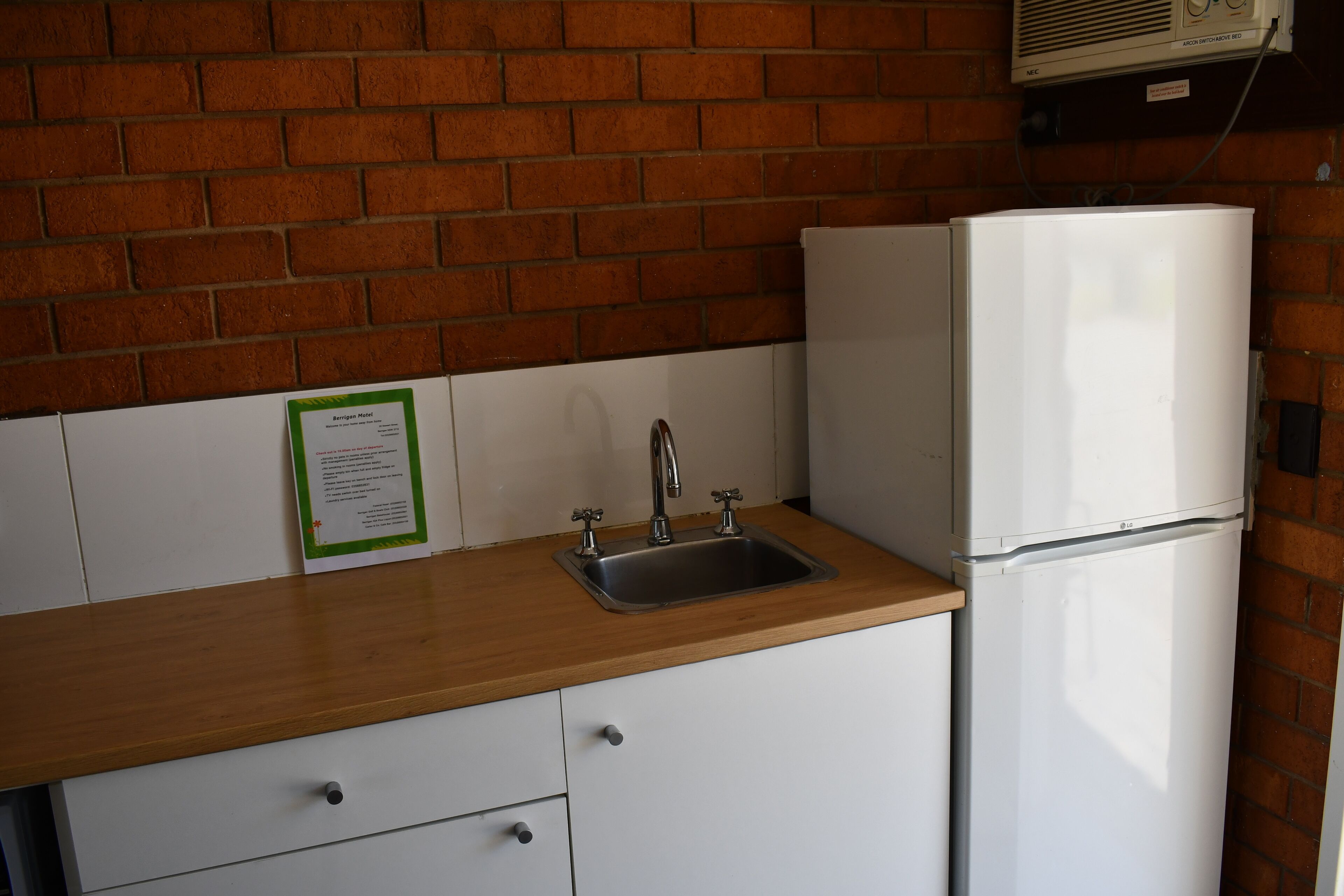 Uma cozinha com pia, geladeira e bancada de madeira.