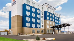 Um hotel Comfort Inn & Suites com design moderno, apresentando um telhado plano, várias janelas e uma área de entrada coberta.