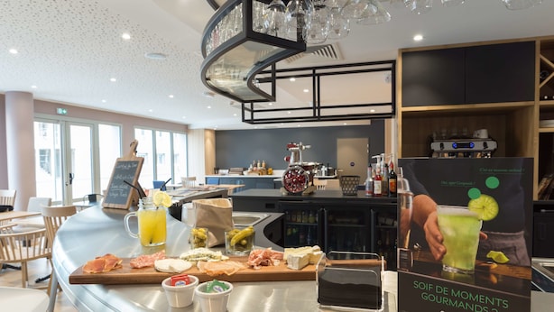Um bar moderno com diversas opções de comida e bebida, incluindo seleção de queijos, carnes e um coquetel.