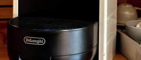 Uma máquina de café DeLonghi com design preto e branco, apoiada em uma superfície de madeira.