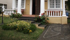 Um edifício de dois andares com entrada central, varanda e pequeno alpendre.